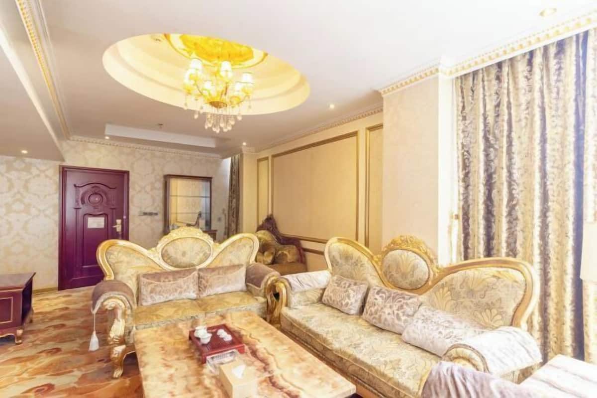 Uma sala de estar luxuosa com sofás ornamentados, um candelabro e um tapete estampado.