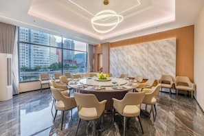 Uma sala de conferências moderna com uma mesa redonda, várias cadeiras e vista para a cidade.