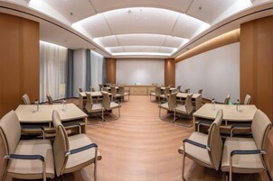 Uma sala de conferências com uma mesa comprida e cadeiras, um pódio e uma janela grande com cortinas.