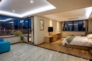 Quarto de hotel moderno com uma cama grande, uma escrivaninha, uma televisão e uma varanda com vista.