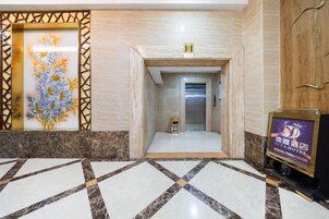 Um saguão de hotel com piso de mármore, balcão de recepção e uma placa.