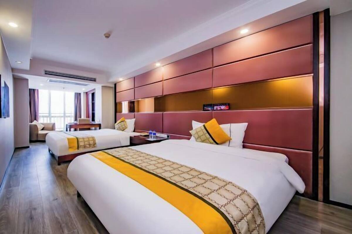 Quarto de hotel com duas camas, uma janela grande e design moderno.