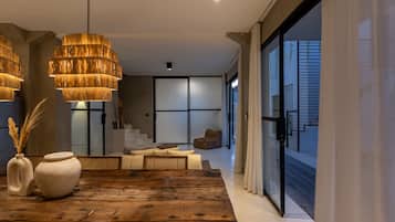 Um interior moderno com uma mesa de jantar de madeira, dois vasos de cerâmica e uma janela grande com vista para um edifício.