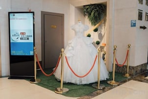Um manequim vestido de branco com uma corda de segurança vermelha bloqueando uma porta fechada.