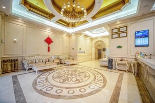 Um hall amplo com piso circular estampado, um lustre e um balcão de recepção.