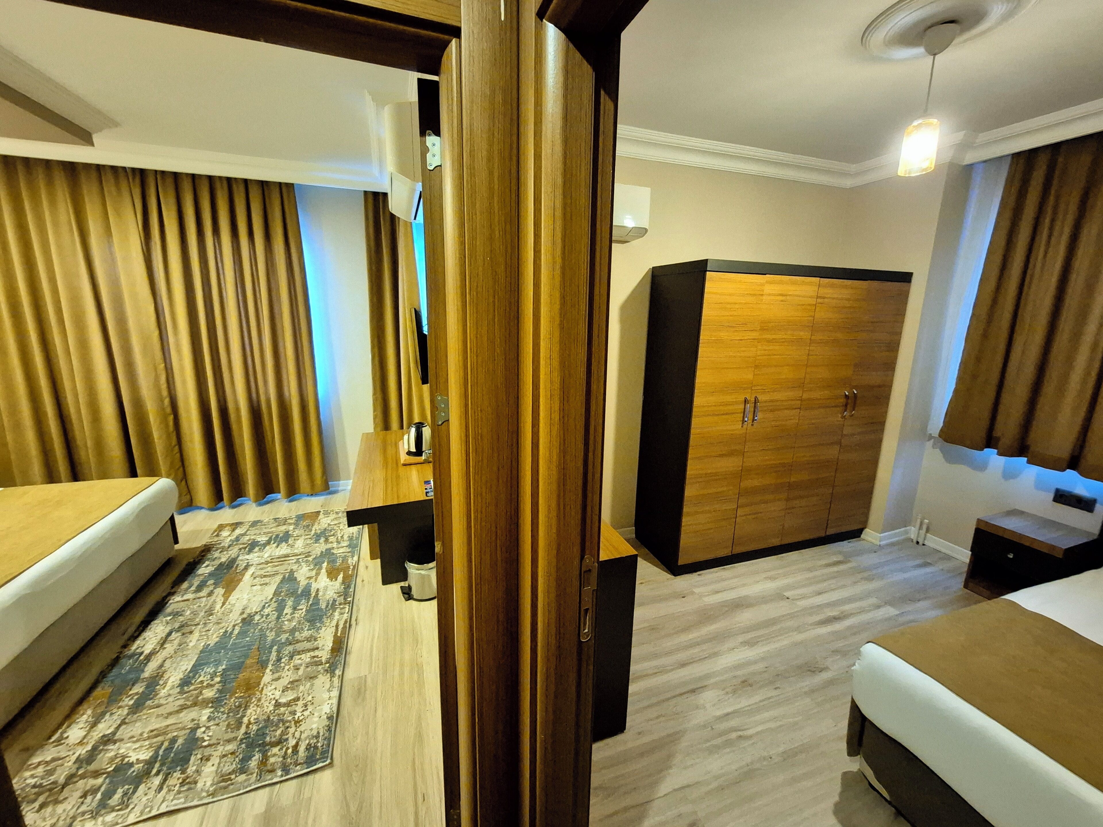 Quarto de hotel com cama, guarda-roupa de madeira, escrivaninha e máquina de café.