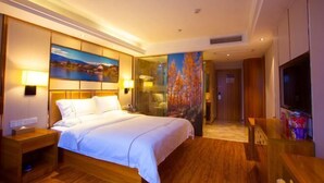 Quarto de hotel com uma cama grande, mesas de cabeceira, televisão e um quadro na parede.