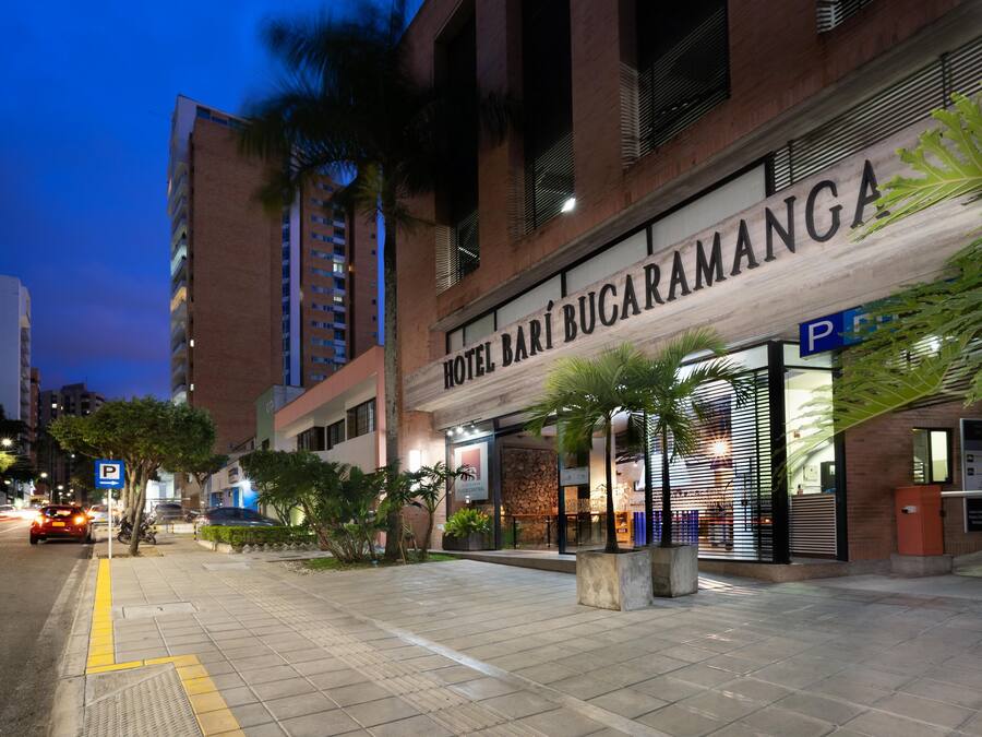 Um hotel chamado "HOTEL BARÍ BUCARAMANGA" com fachada moderna, uma placa de estacionamento e uma entrada bem iluminada.
