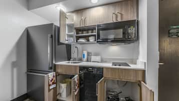 Cozinha compacta com frigorífico, micro-ondas e máquina de lavar loiça.
