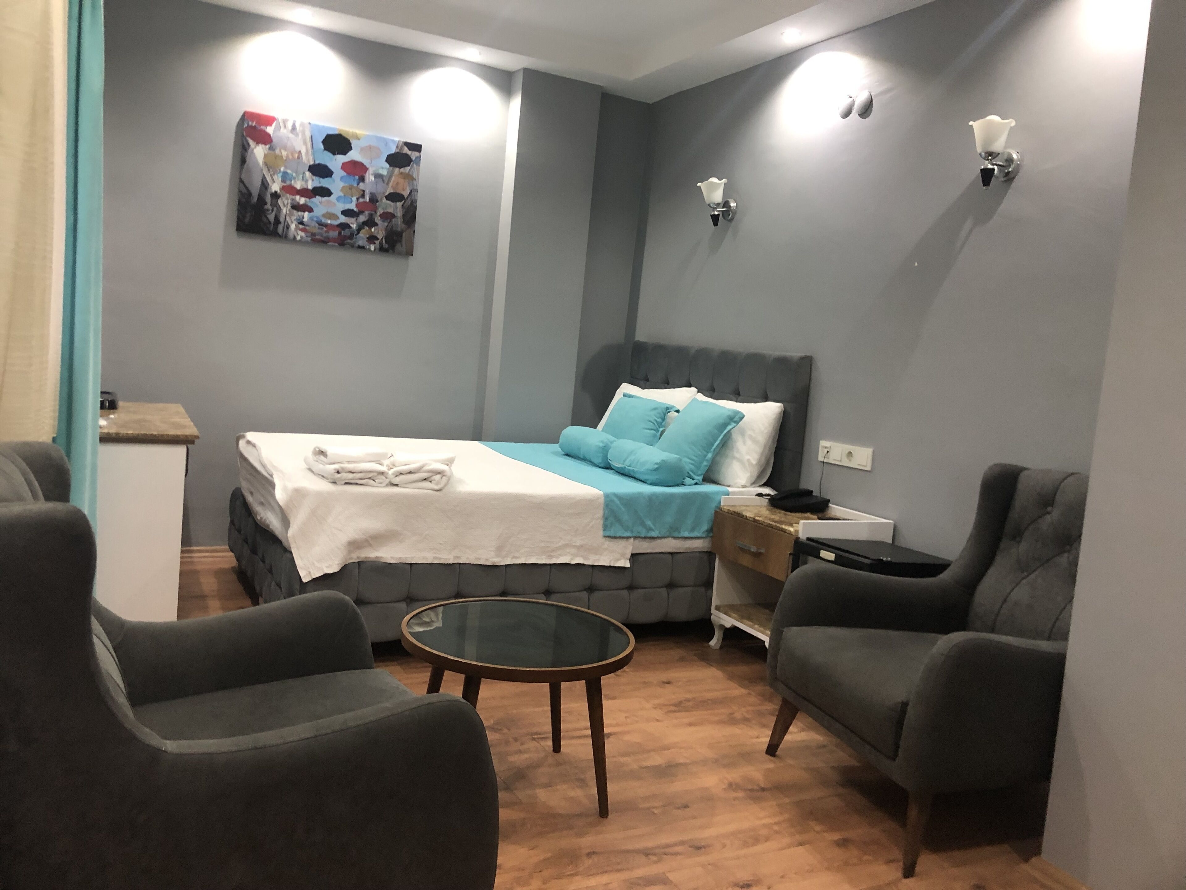 Quarto moderno com uma cama, duas poltronas, uma mesinha e uma mesa de cabeceira.