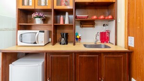 Cozinha com armários de madeira, micro-ondas, cafeteira e pia.