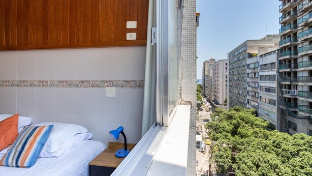 Quarto de hotel com cama, secretária e vista para a rua da cidade.