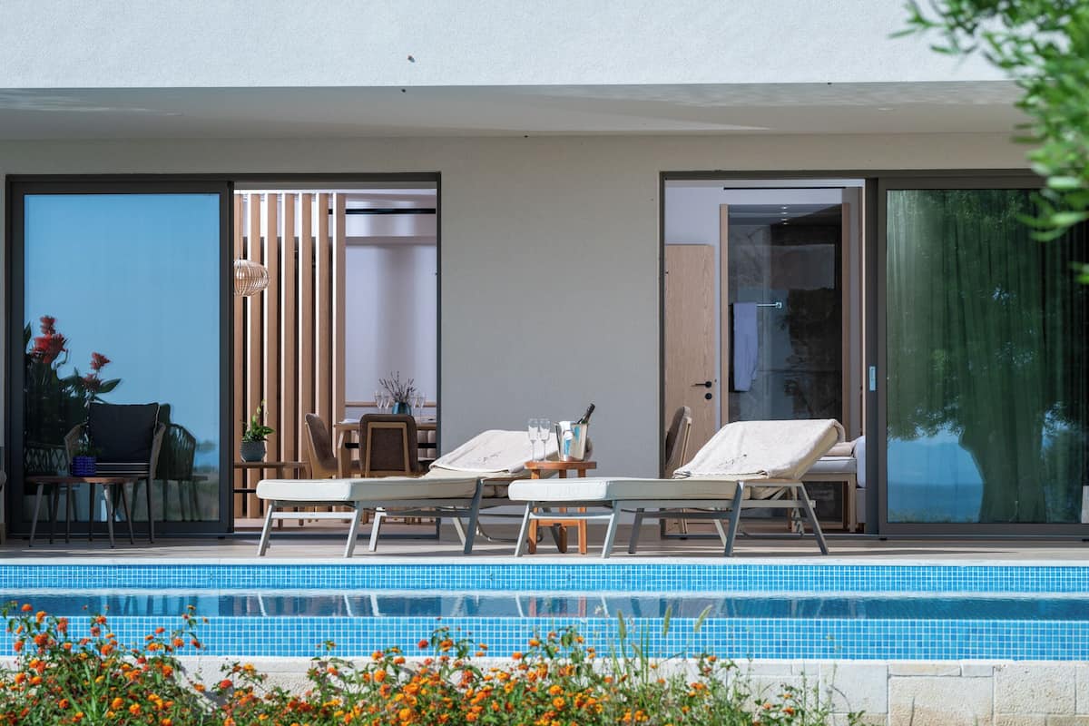 Uma área moderna com piscina ao ar livre, cadeiras de descanso e uma mesa de jantar.