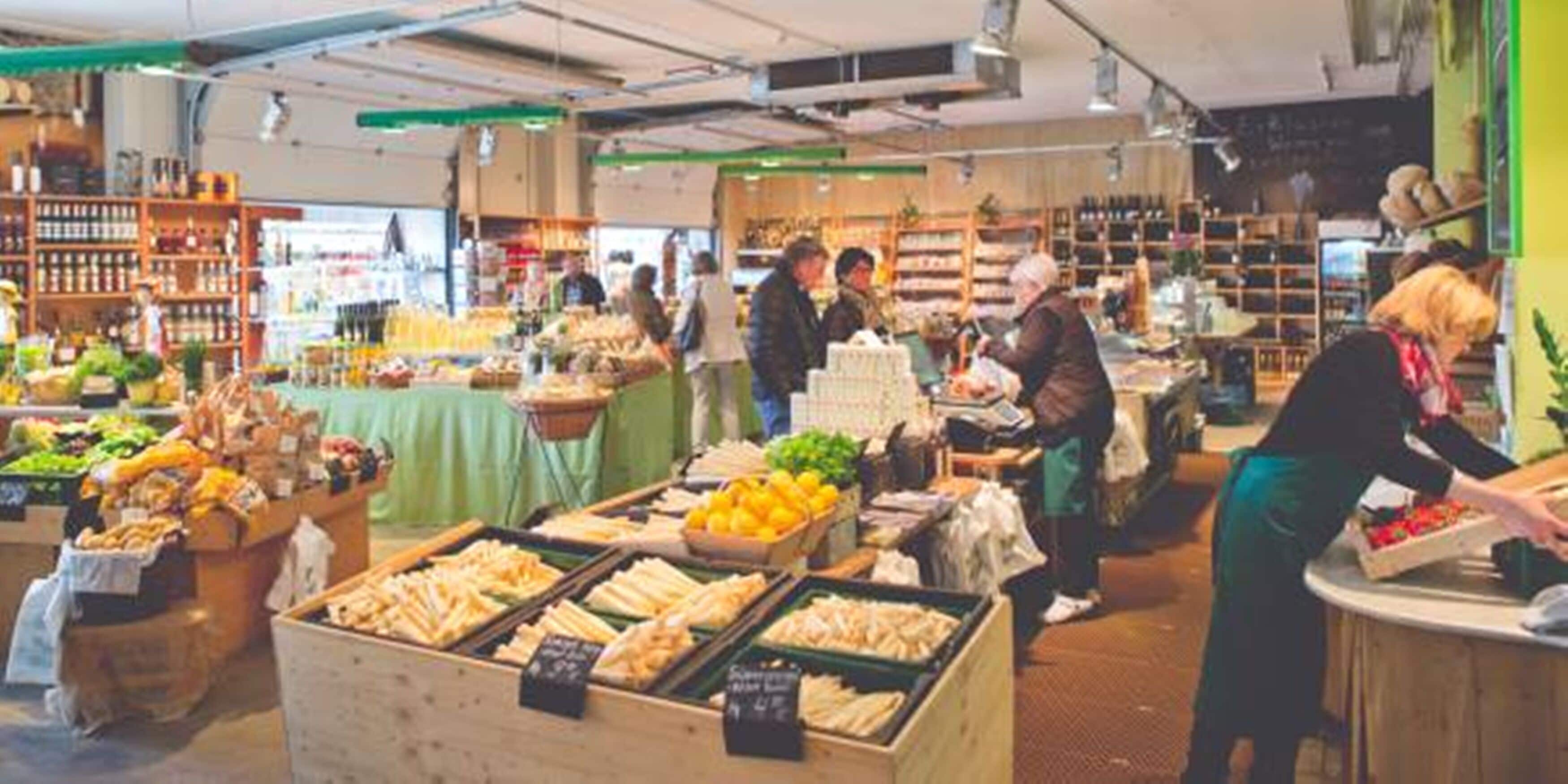 Um mercado interno movimentado com vários quiosques vendendo produtos frescos, pão e outros artigos.