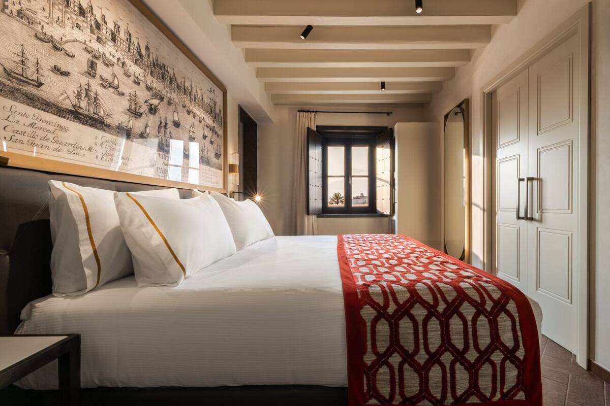 Quarto de hotel com uma cama grande, um adorno de parede e uma janela com cortinas.