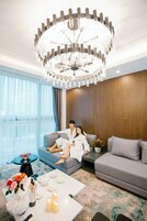 Uma sala de estar moderna com um lustre grande, sofás cinza e uma mesa de centro com objetos decorativos.