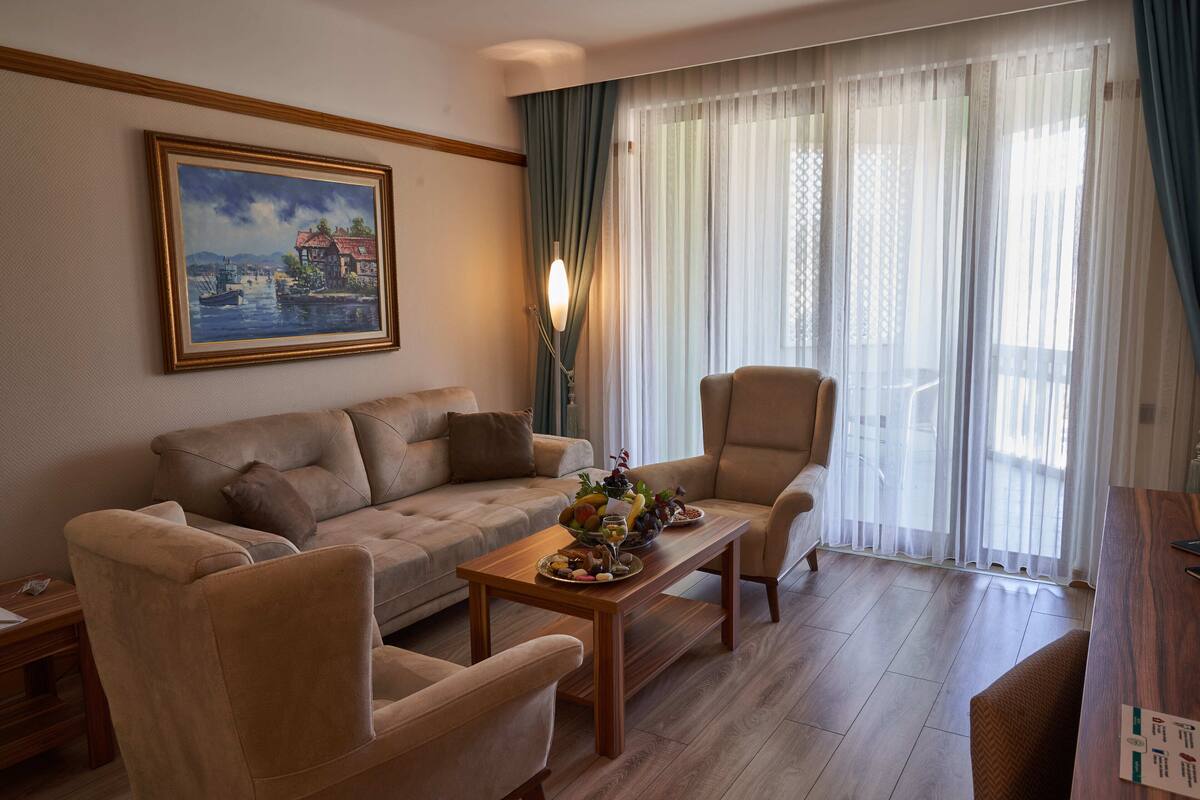 Sala de estar com sofá, poltronas, mesa de centro com frutas e um quadro na parede.