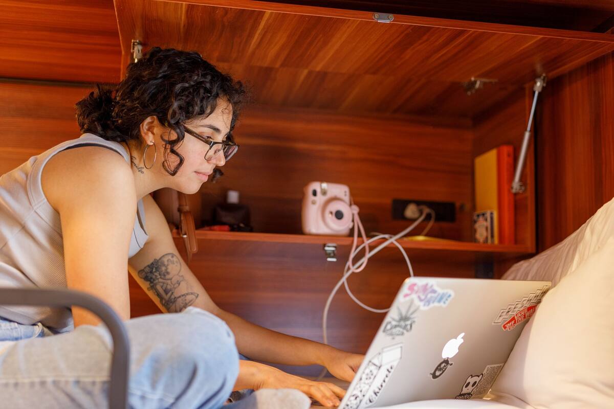 Uma pessoa usando um laptop em um quarto com paredes e prateleiras de madeira.