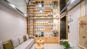 Um interior moderno com um sofá, duas mesas redondas e diversos objetos nas prateleiras.
