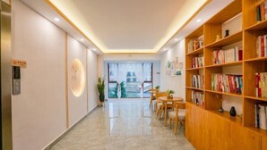 Um hall de hotel com piso de mármore, um balcão de recepção, uma estante de livros e vista através de uma grande janela.