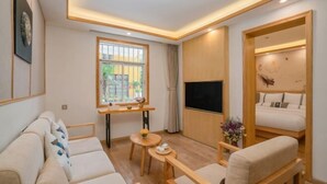 Quarto moderno com sofá, uma mesa pequena, televisão e cama.
