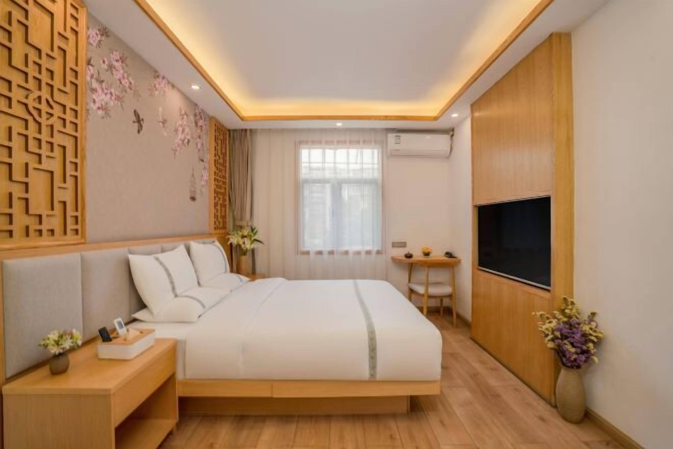 Quarto moderno com cama, mesa de cabeceira, TV e painéis decorativos na parede.