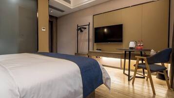 Quarto de hotel com cama, escrivaninha, cadeira, televisão de tela plana e cafeteira.