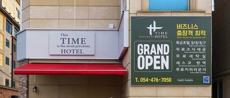 Placa de hotel com 'TIME Business Hotel' e 'Grande Abertura', indicando disponibilidade.