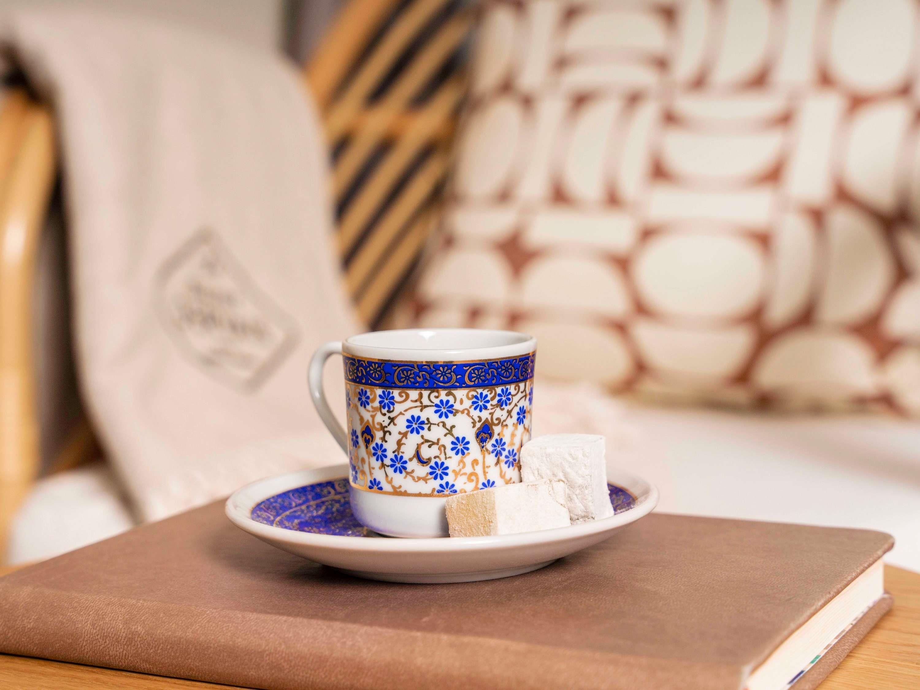 Uma chávena com padrão floral, um pires e um livro sobre uma mesa.