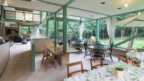 Um espaço interno amplo com uma mesa de jantar, cadeiras e vista para o exterior.