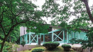 Um edifício com arquitetura moderna, rodeado por vegetação exuberante e árvores.