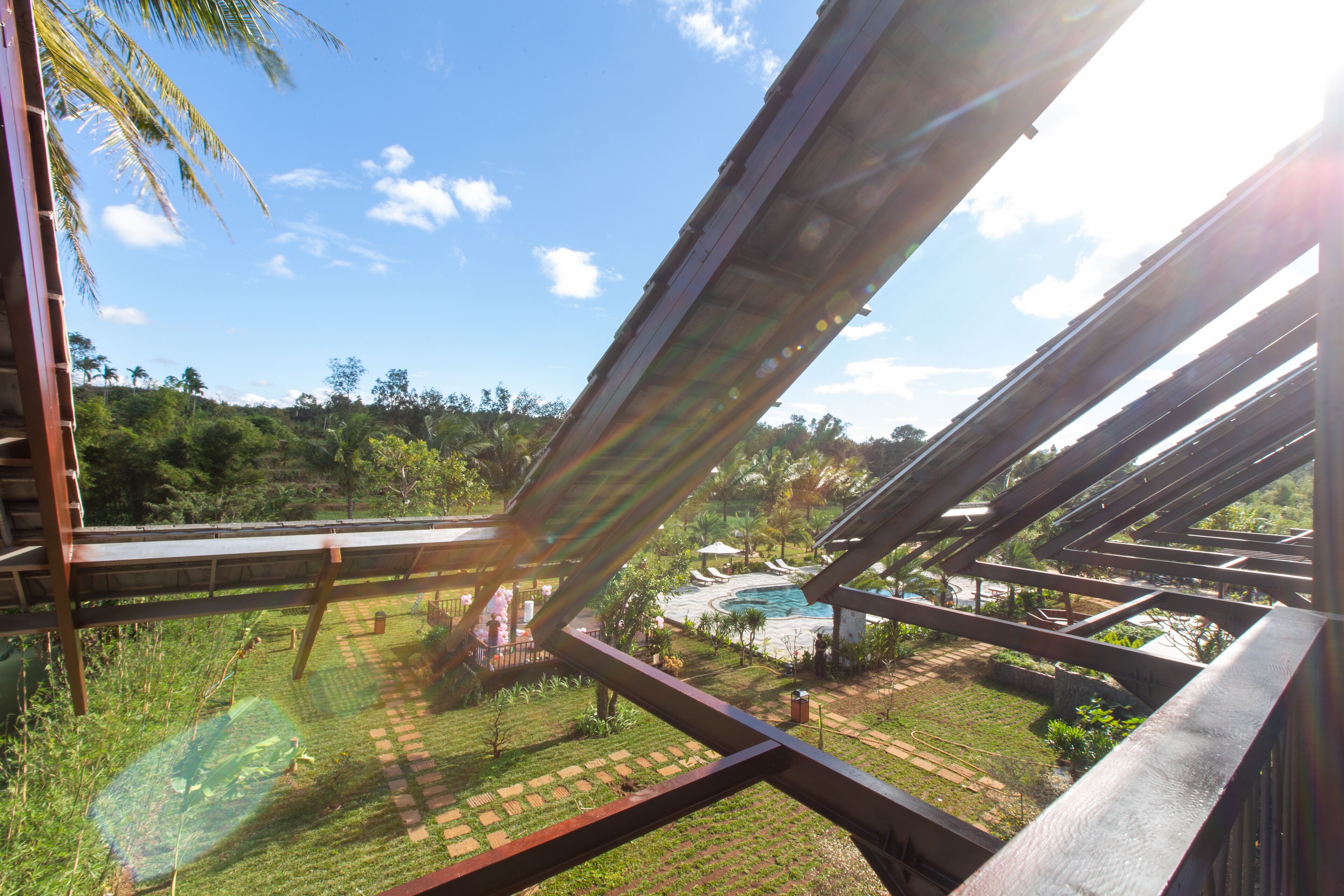 Vista de um ponto alto, com vista para área de piscina, céu limpo e vegetação exuberante.
