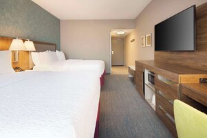 Quarto de hotel com uma cama grande, uma escrivaninha e uma televisão de tela plana, e um closet espaçoso.