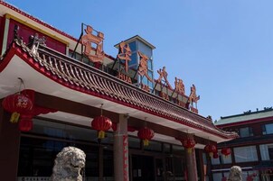 Um edifício com elementos arquitetônicos tradicionais chineses, incluindo esquema de cores vermelho e branco, decoração ornamental no telhado e lanternas vermelhas.