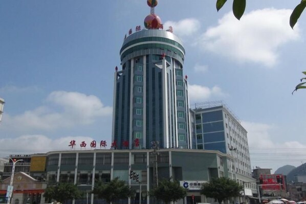 Um edifício com vários andares e uma torre cilíndrica, com um sinal vermelho e branco chamativo na base.