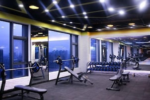 Uma academia com equipamentos de musculação, bancos e halteres.
