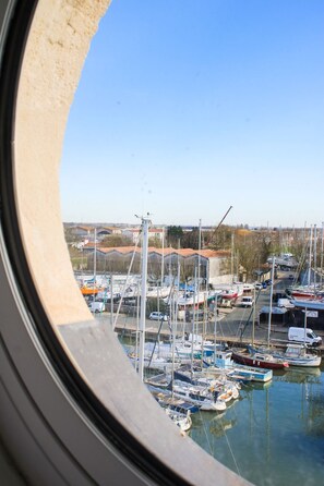 Uma marina com vários barcos atracados, céu claro e edifícios ao fundo.