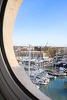 Uma marina com vários barcos atracados, céu claro e edifícios ao fundo.