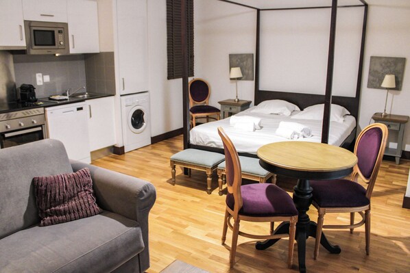 Quarto de hotel com cama, mesa de jantar e cadeiras, sofá, máquina de lavar e micro-ondas.