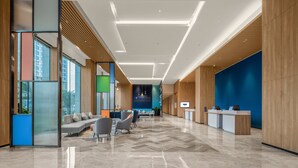 Um lobby moderno com balcão de recepção, área de estar e grandes janelas.