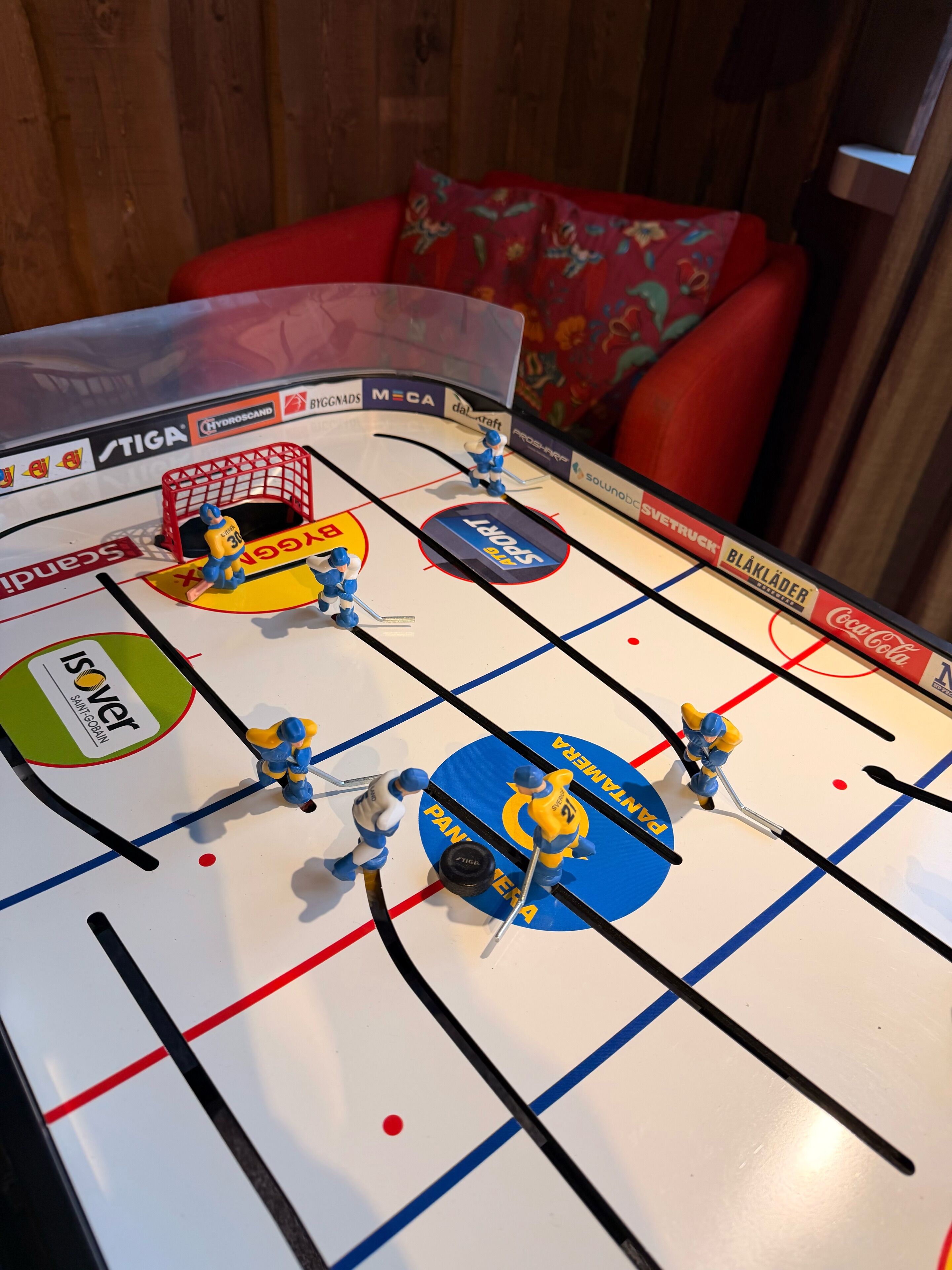 Uma pista de hóquei no gelo em miniatura, com jogadores e uma baliza.
