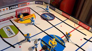 Uma pista de hóquei no gelo em miniatura, com jogadores e uma baliza.