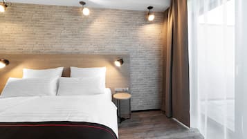 Quarto de hotel moderno com parede texturizada em tijolos, cabeceira de madeira e mesa de cabeceira redonda.