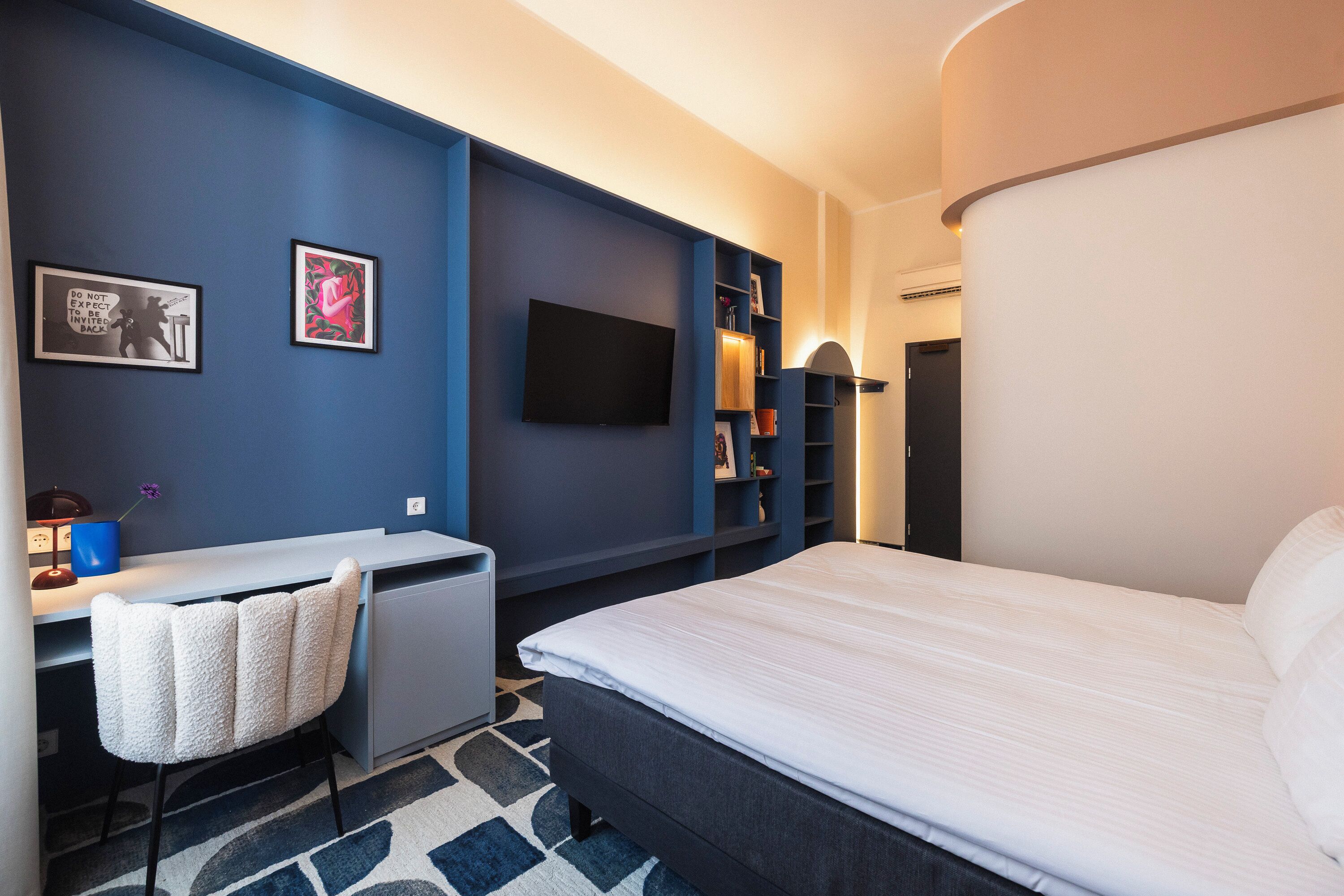 Quarto de hotel moderno com cama, escrivaninha e área de estar.