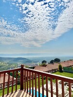 Terraço com piscina e mobiliário de exterior, com vista para uma paisagem com campos em socalcos e montanhas ao longe.