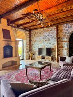 Uma sala de estar acolhedora com lareira de pedra, televisão e um sofá confortável.