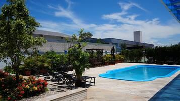 Piscina com espreguiçadeiras e plantas em vasos.