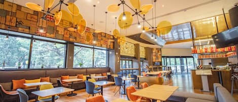 Um restaurante moderno com pé-direito alto, amplas janelas e diversas opções de assentos, incluindo mesas e cabines.