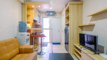 Um espaço compacto para relaxar, com sofá, televisão, cozinha compacta e banheiro.