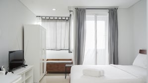 Quarto de hotel moderno com cama, televisão, escrivaninha e guarda-roupa.